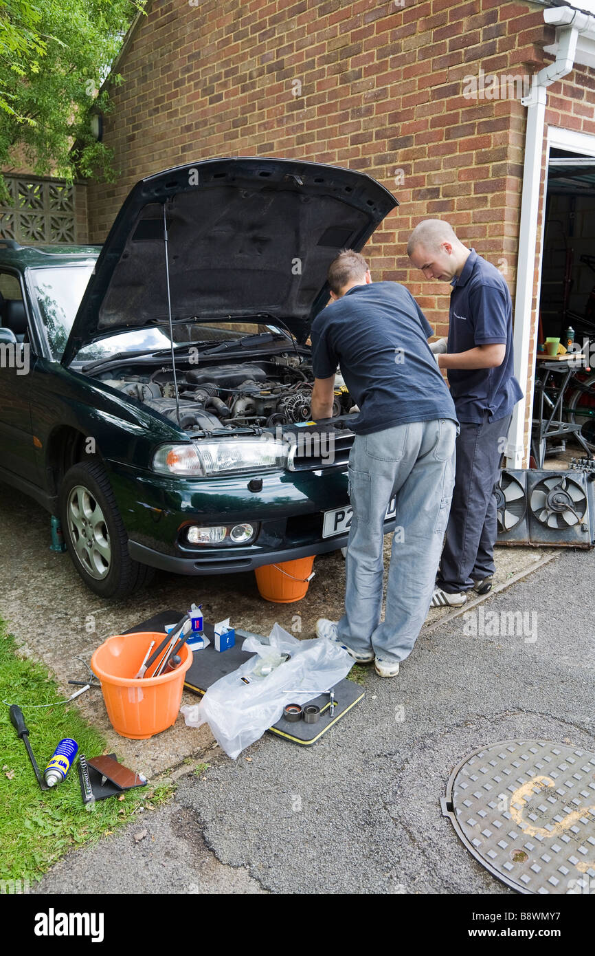 Two young mechanics servicing a car in a driveway Stock Photo - Alamy