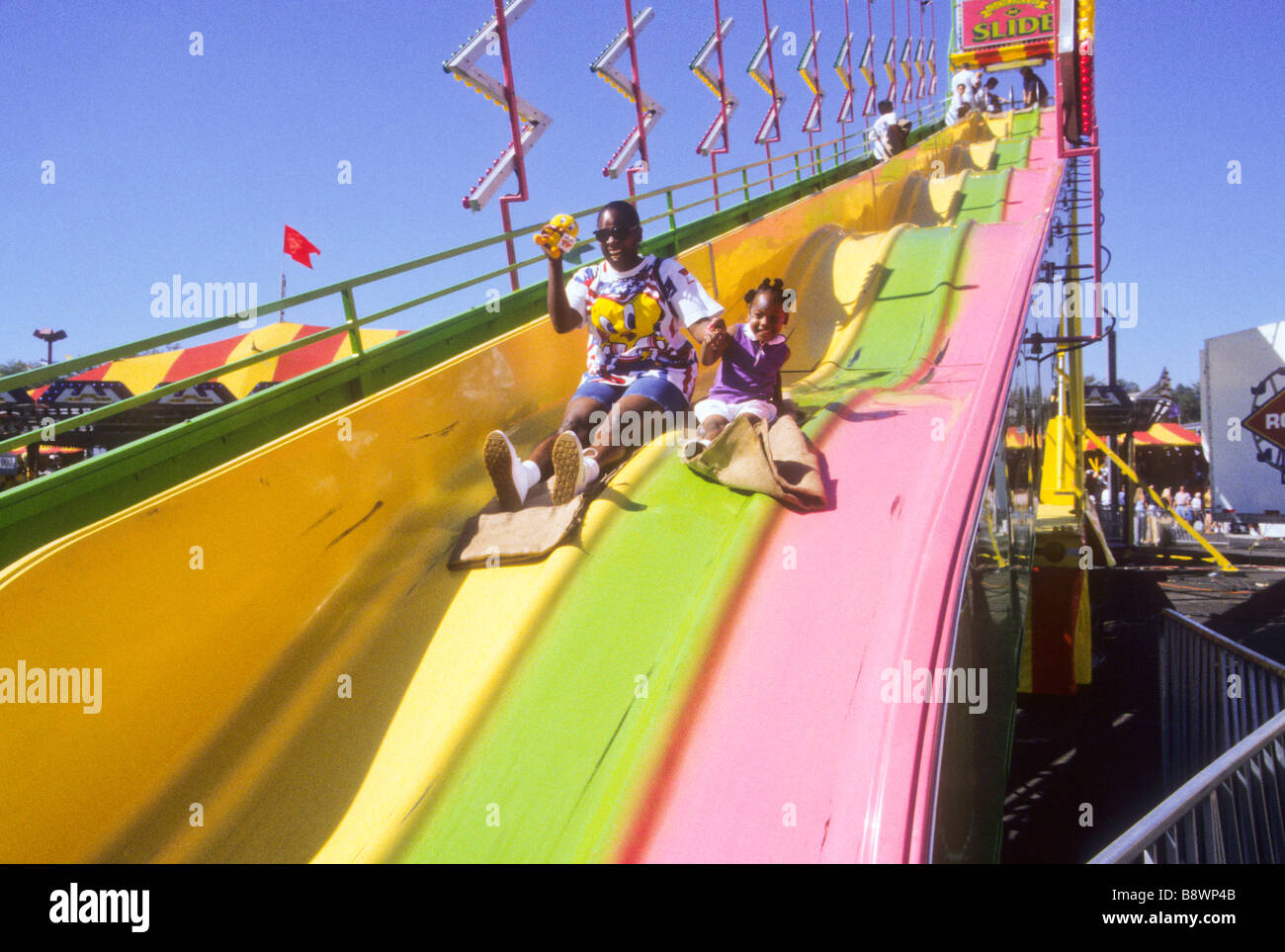 mother mom daughter slide carnival ride thrill fun laugh share support ...