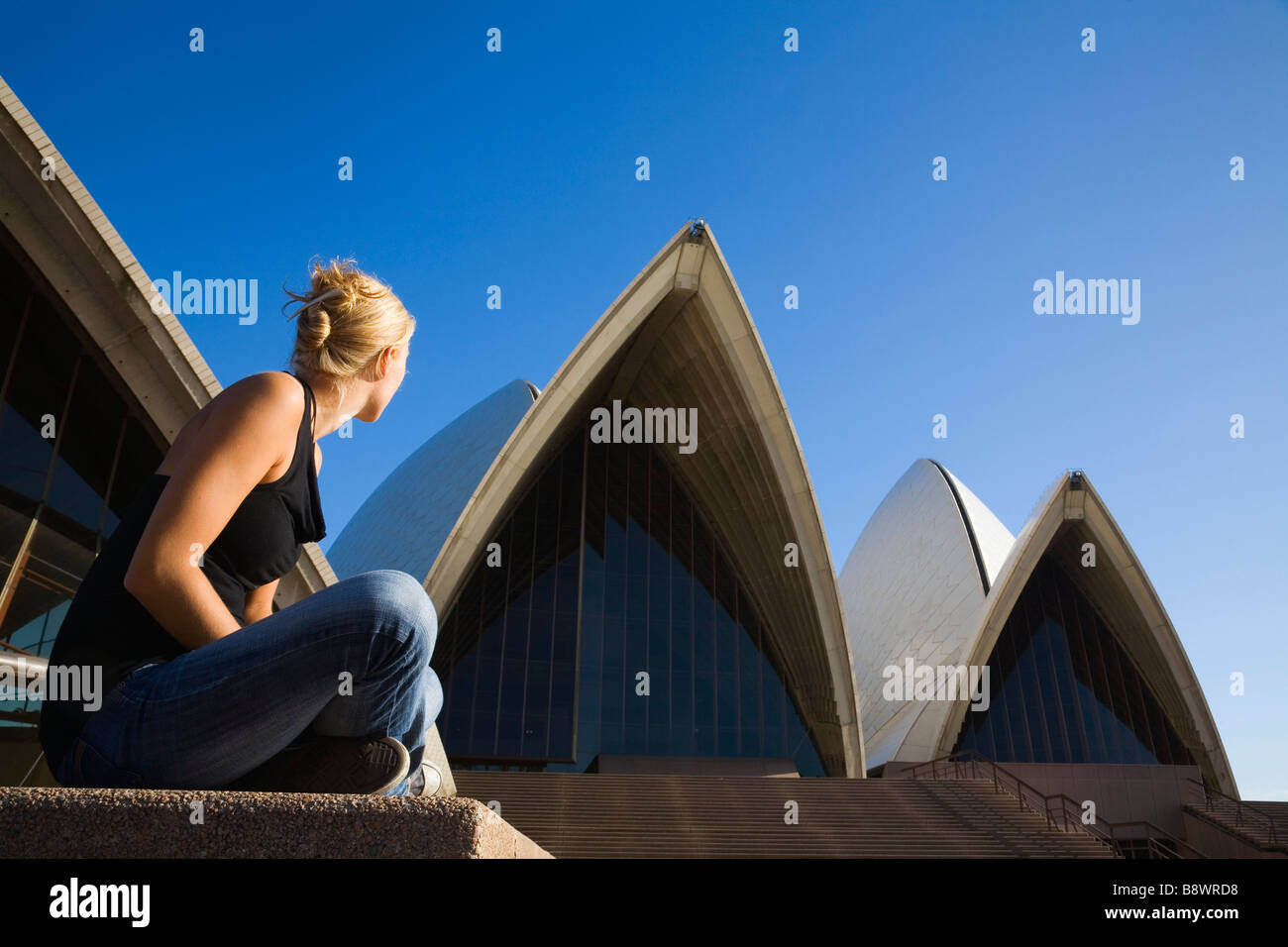 A woman looks up the iconic roofs of the Opera House in Sydney, New ...