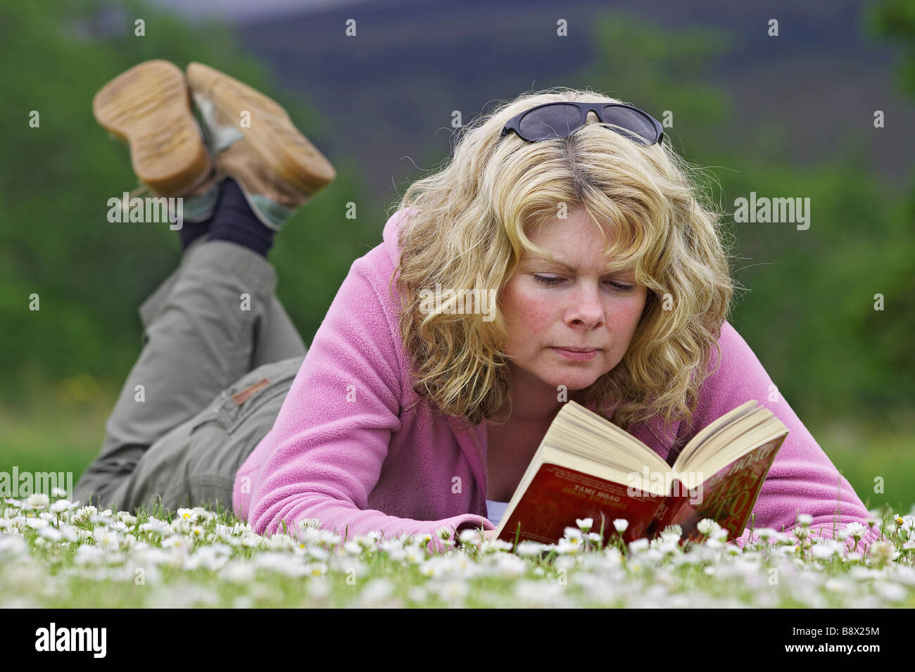 Woman (aged 35-45 years old) led in flower meadow reading book Stock ...