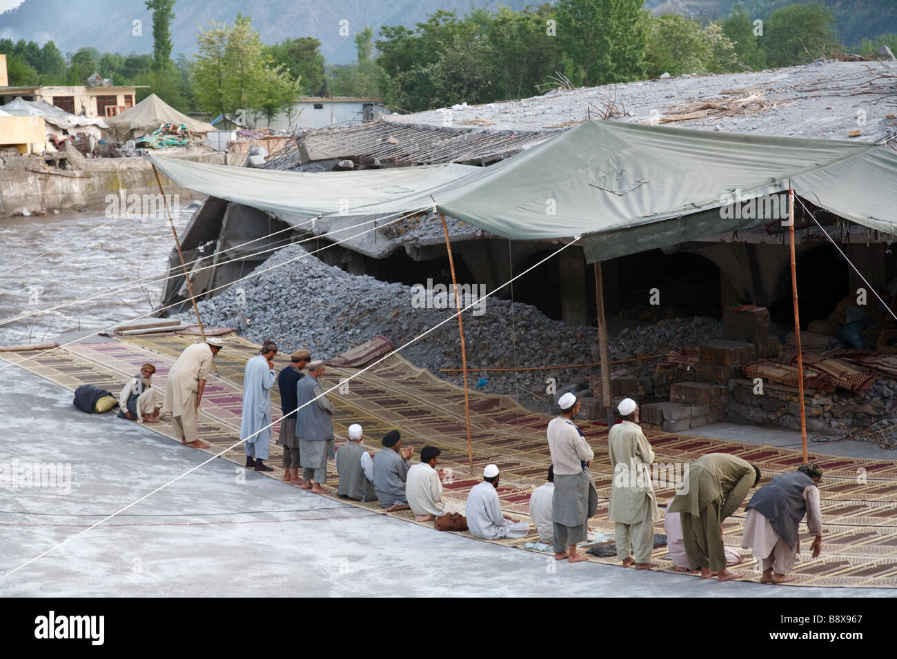 Men gather for evening prayers in the ruins of mosque in Balakot ...