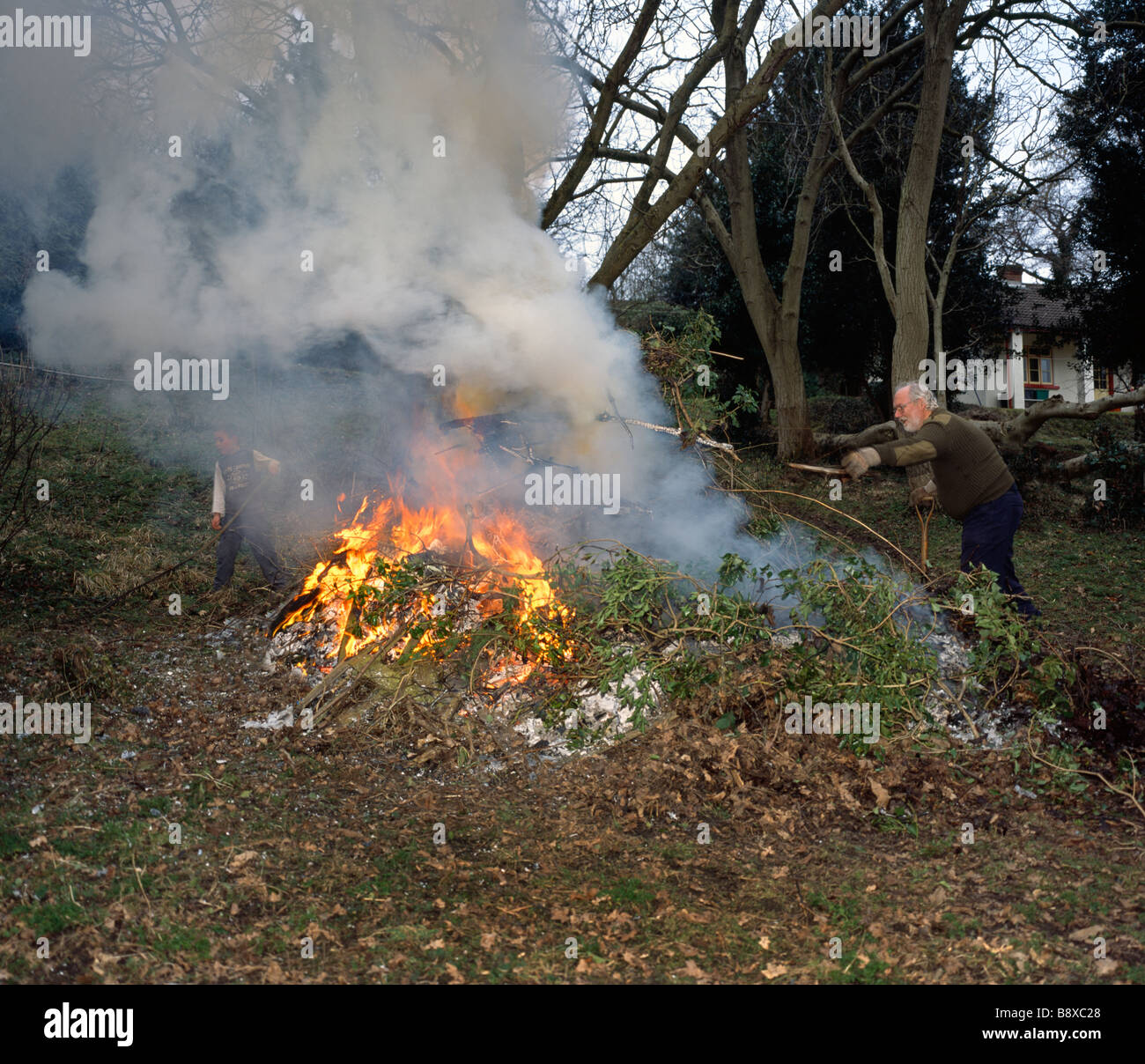 Man and boy tending a bonfire Stock Photo - Alamy