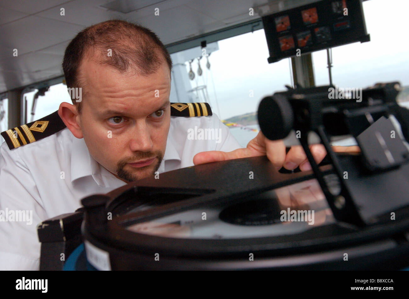 An officer of the Royal Fleet Auxiliary uses a sighting compass on the ...