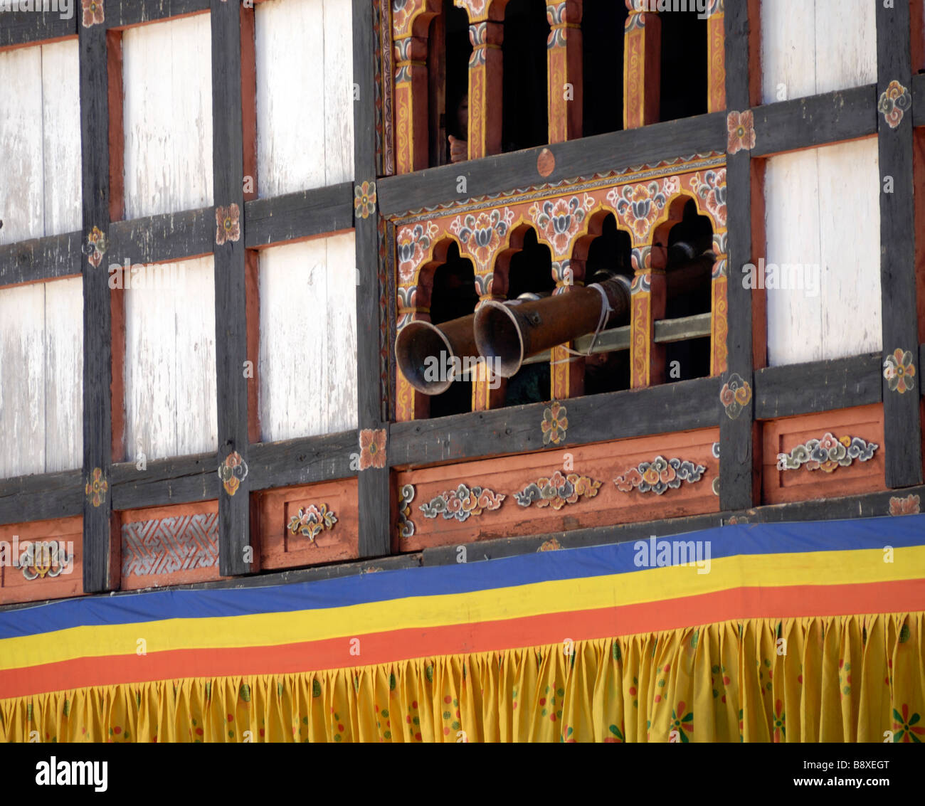 The ends of two long musical bass horns protrude from an ornate window ...