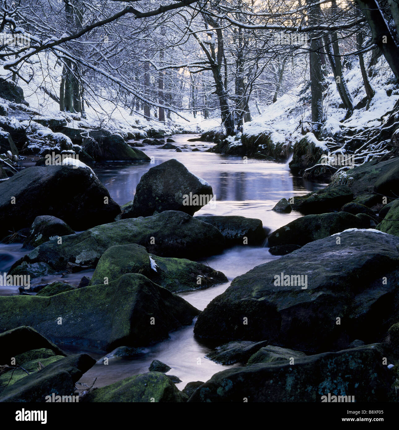 Hebden Water running along its rock strewn bed between the snow covered ...