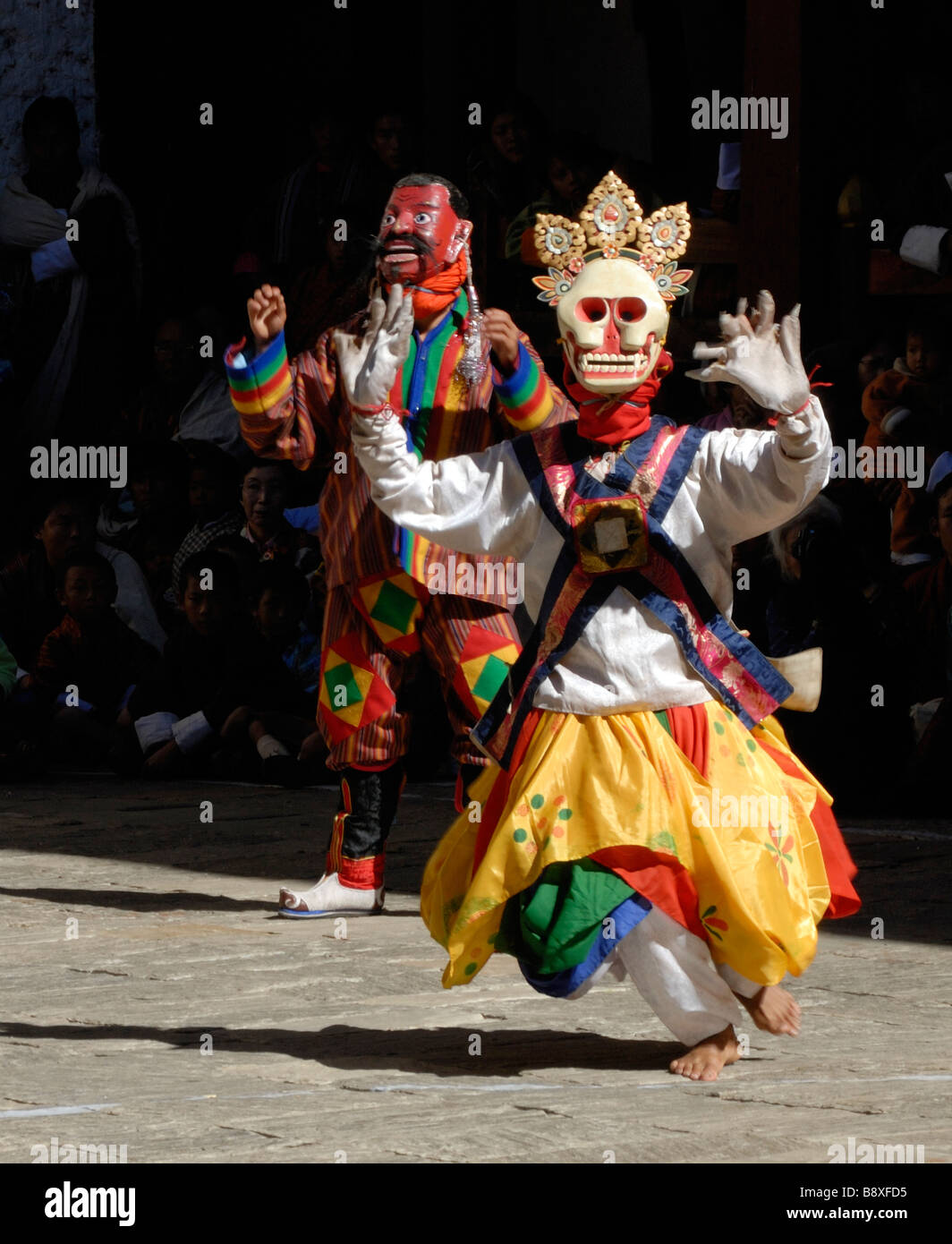 A dancer in a painted skull mask and brightly coloured clothes dances ...