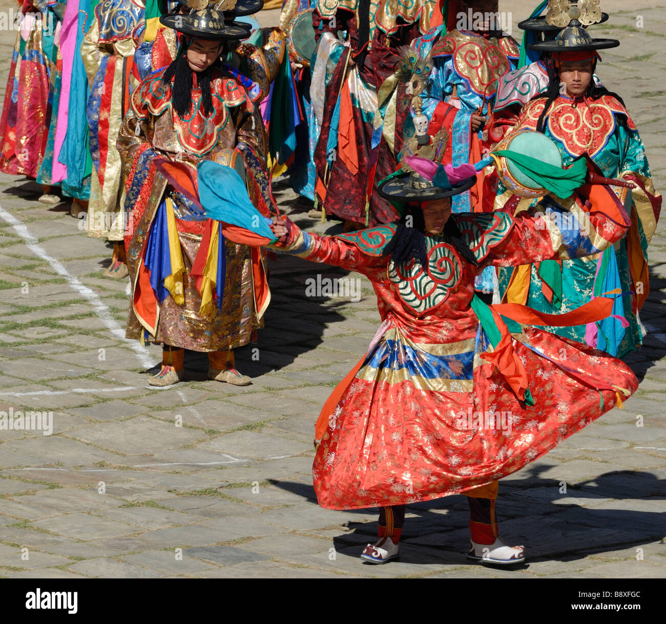 A black hat dancer beating drums and dressed in gorgeous red silk robes ...