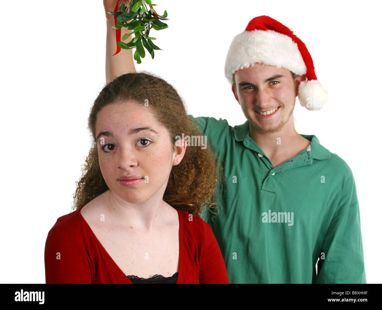 A teen boy holding mistletoe over the head of a teen girl She s not ...