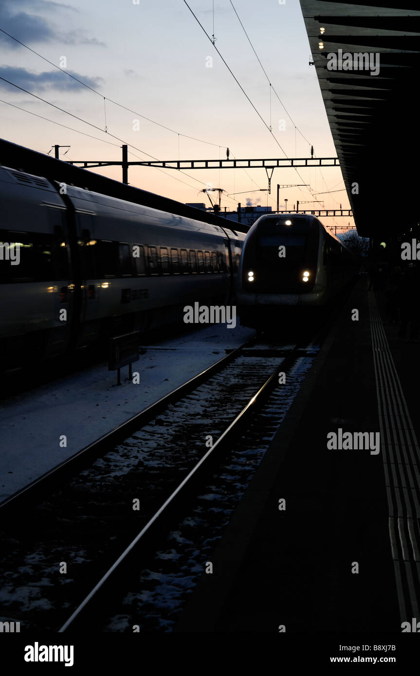 train coming into a swiss switzerland railway station at speed sunset ...