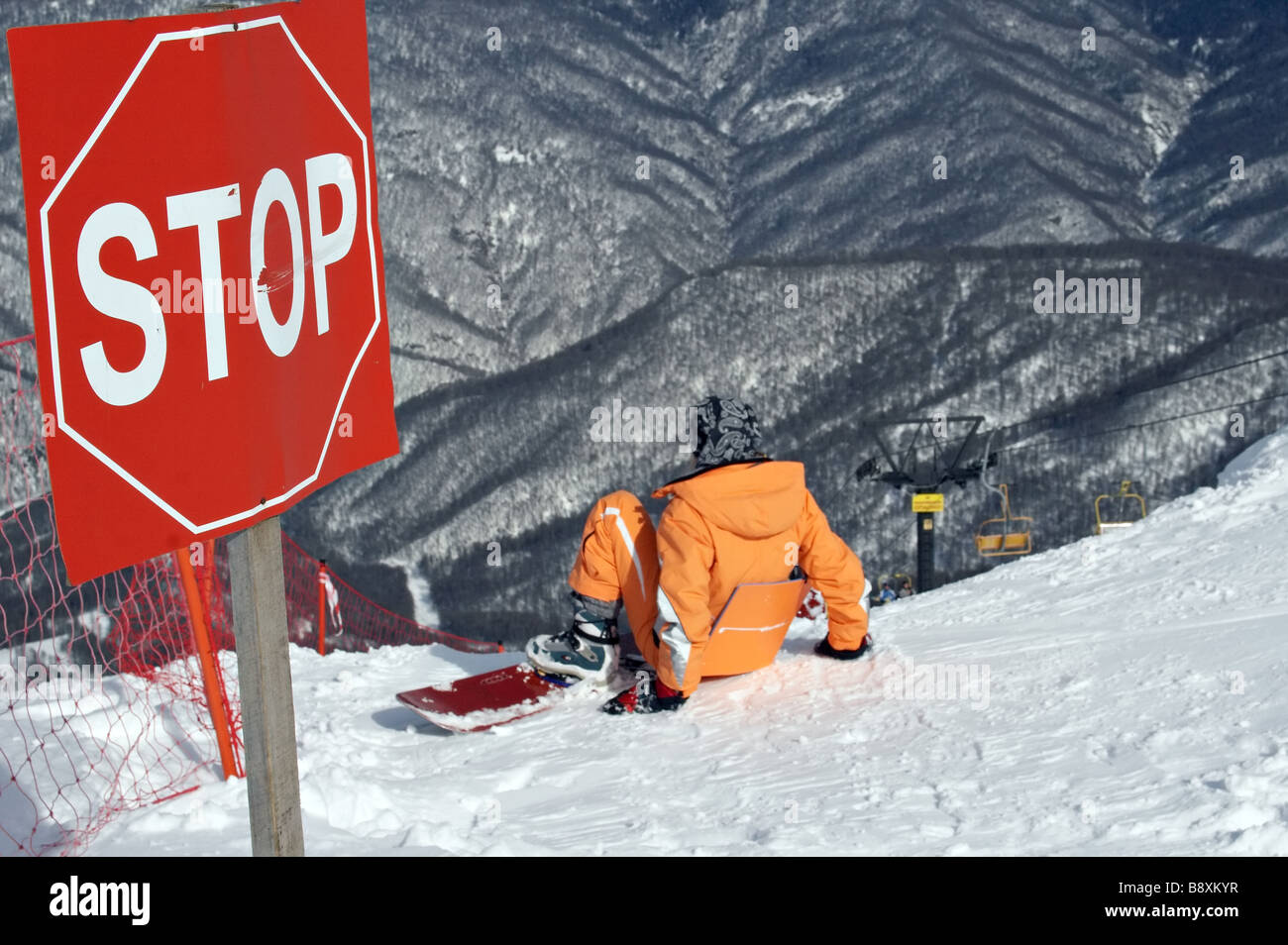 snowborder sitting under stop sign Stock Photo - Alamy