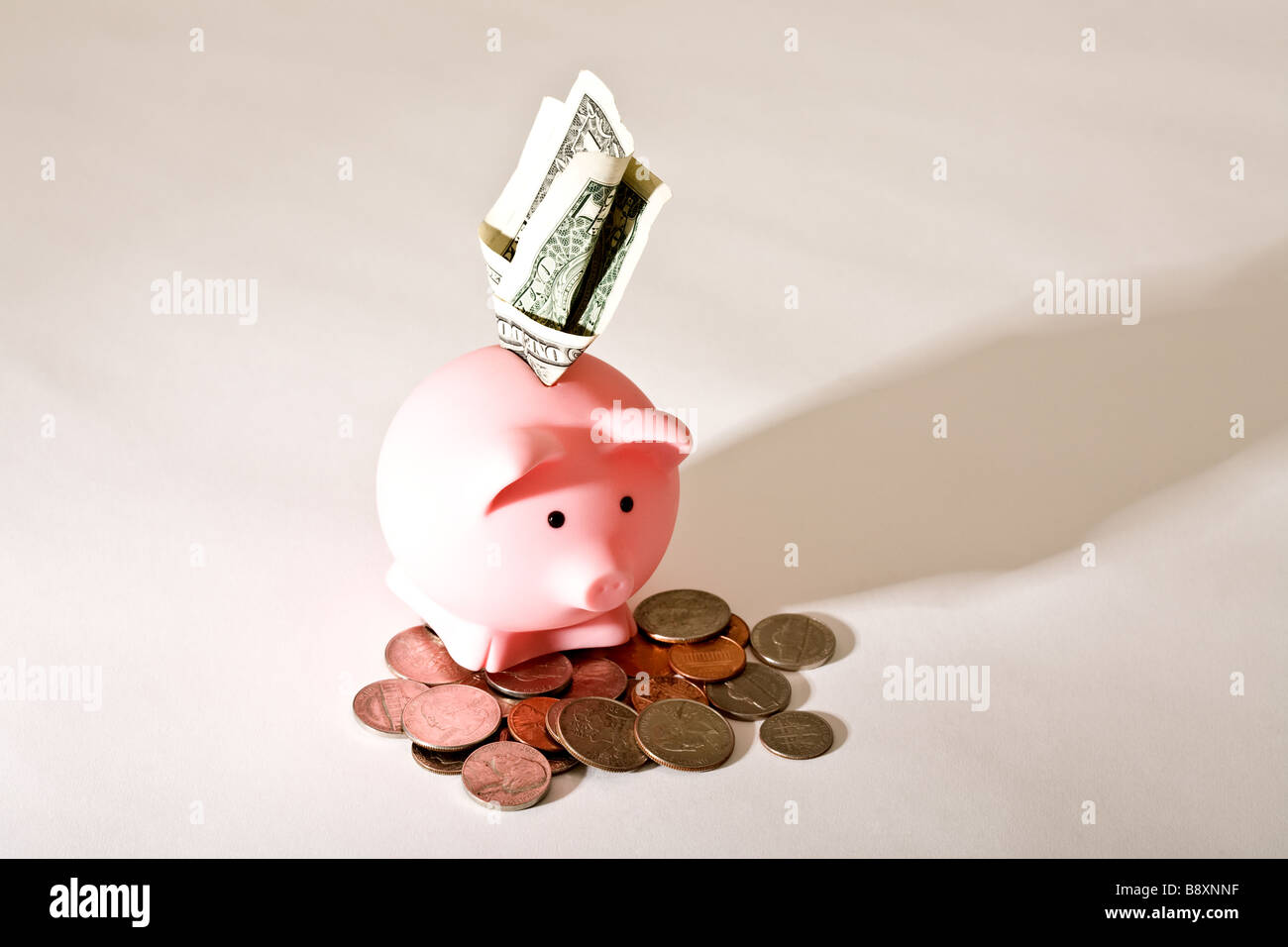 Piggy bank with a dollar bill going in the top and coins spilling out ...