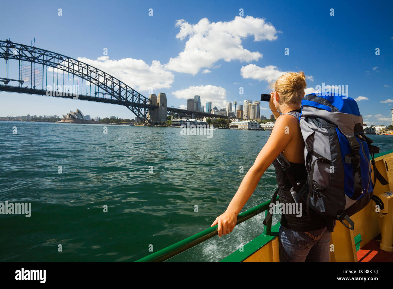A backpacker photographs the Harbour Bridge from aboard a Sydney ferry ...