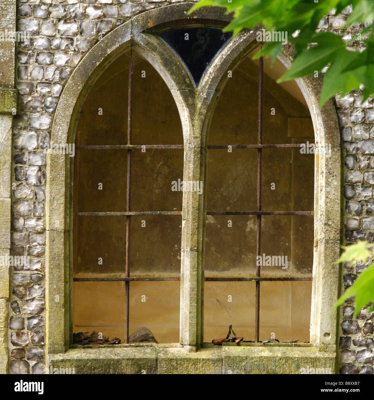 A double arched window with stone mullions set into a flint wall at ...