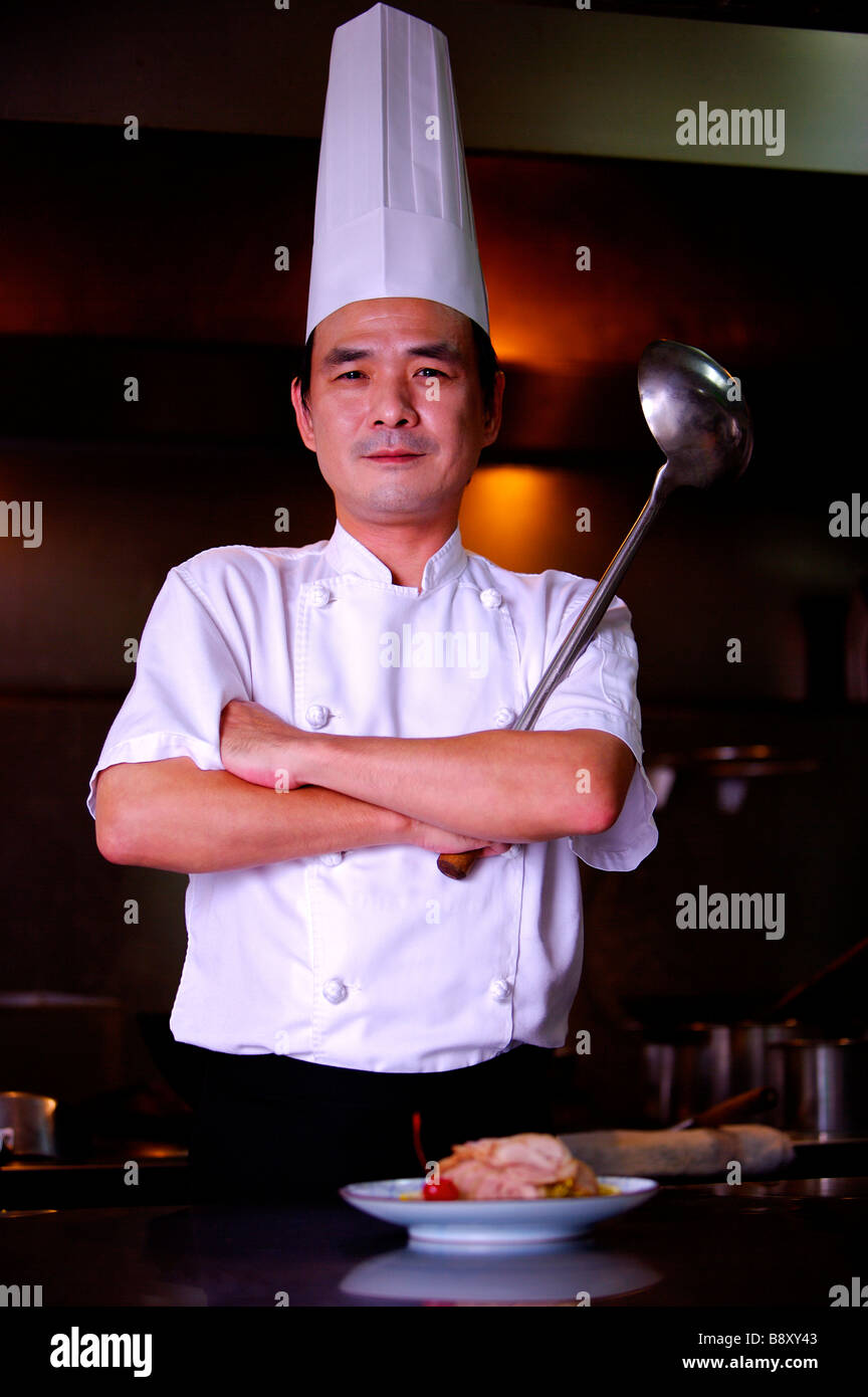 Chef holding a cooking ladle with arms crossed and looking at the ...