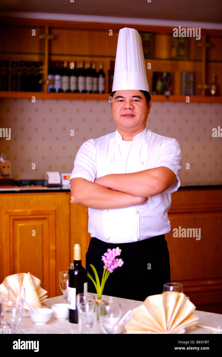 Chef standing near the dinner table with arms crossed and looking at ...