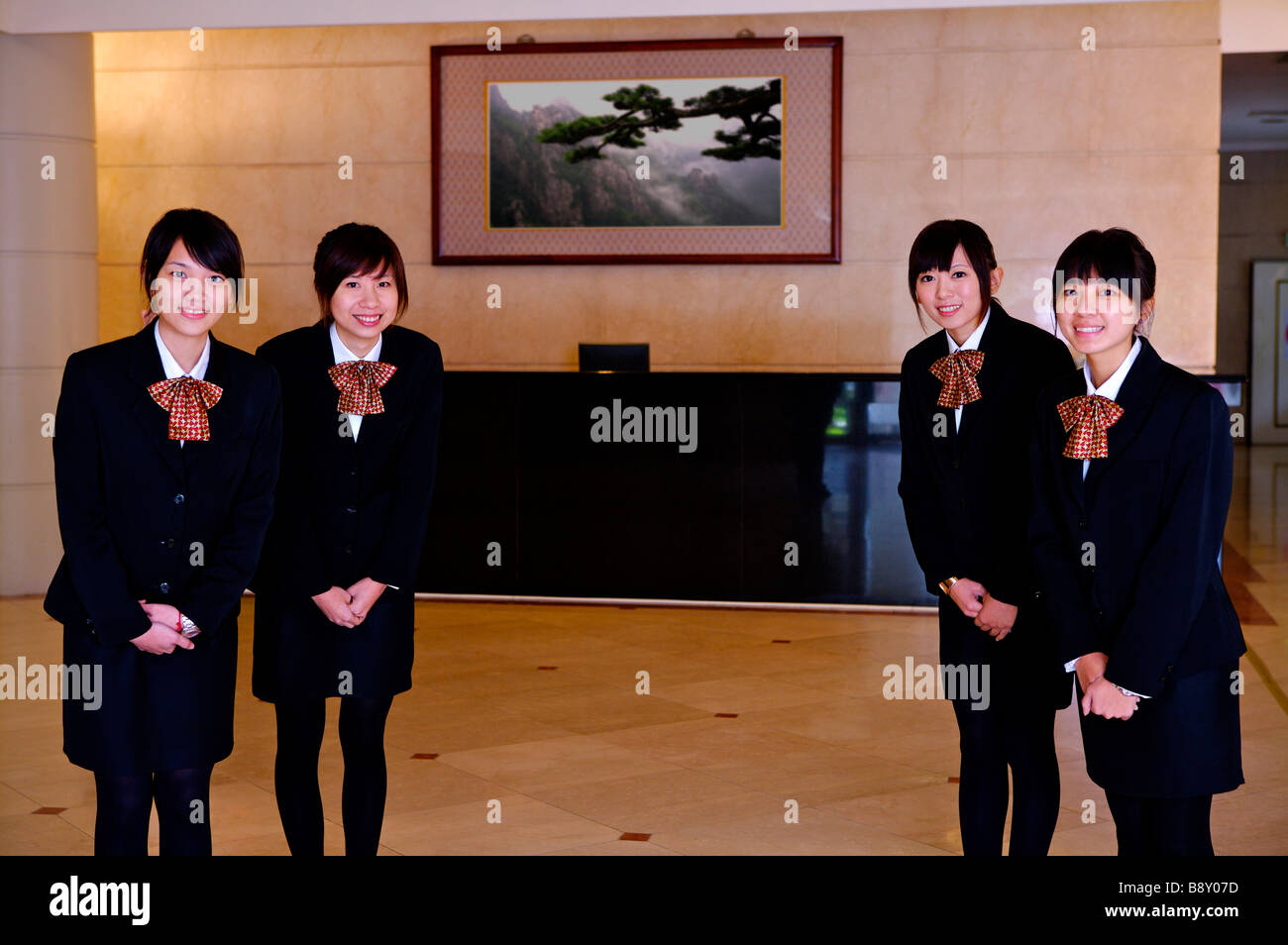 Four young waitresses welcoming guests at the lobby Stock Photo - Alamy