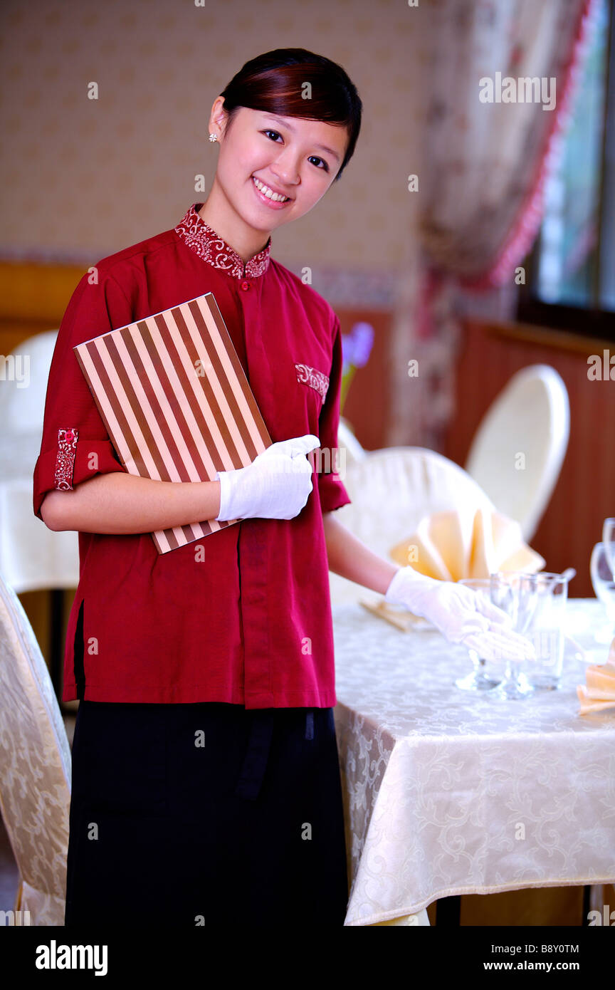 Young waitress holding the menu and smiling at the camera Stock Photo ...