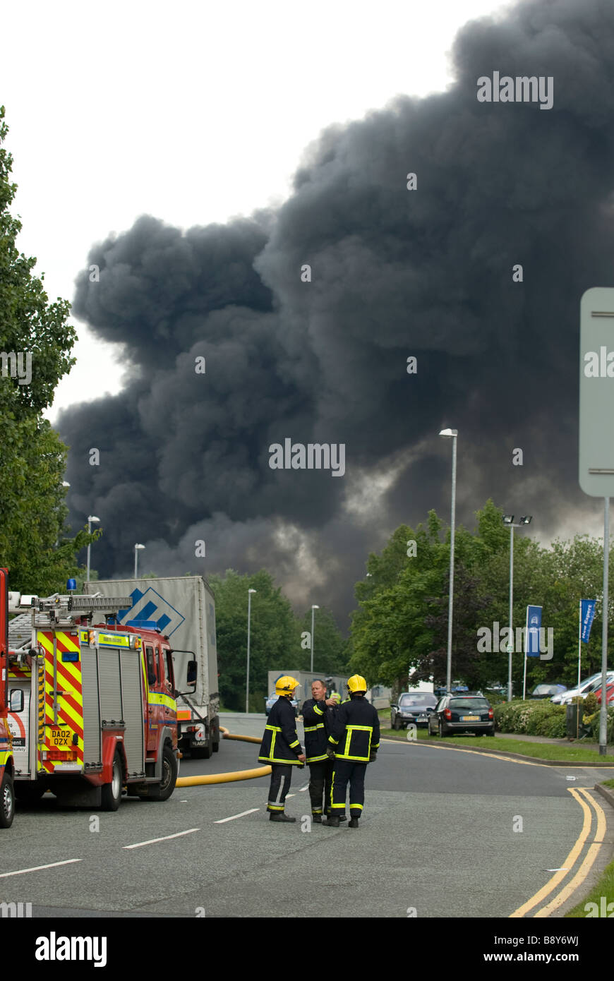 Firemen in front of large plume of smoke at chemical factory fire ...