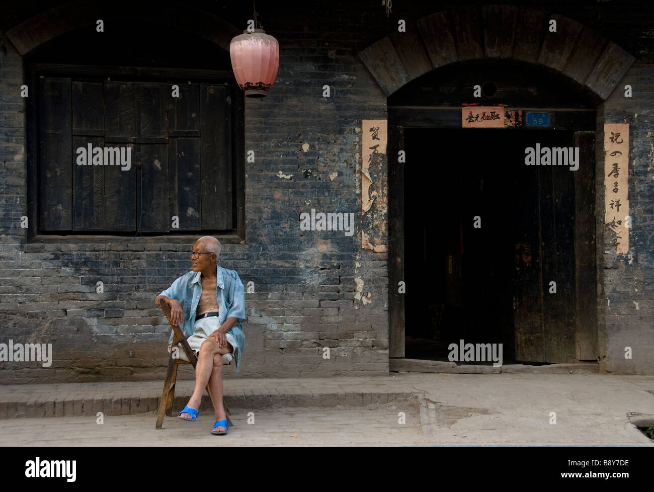 Old Chinese man sitting in of the traditional Streets of Pingyao ...