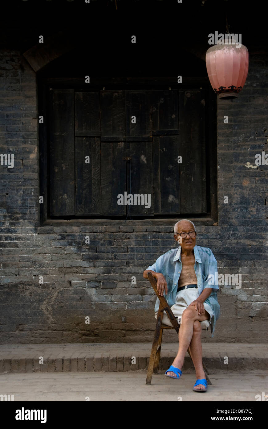 Old Chinese man sitting in of the traditional Streets of Pingyao ...