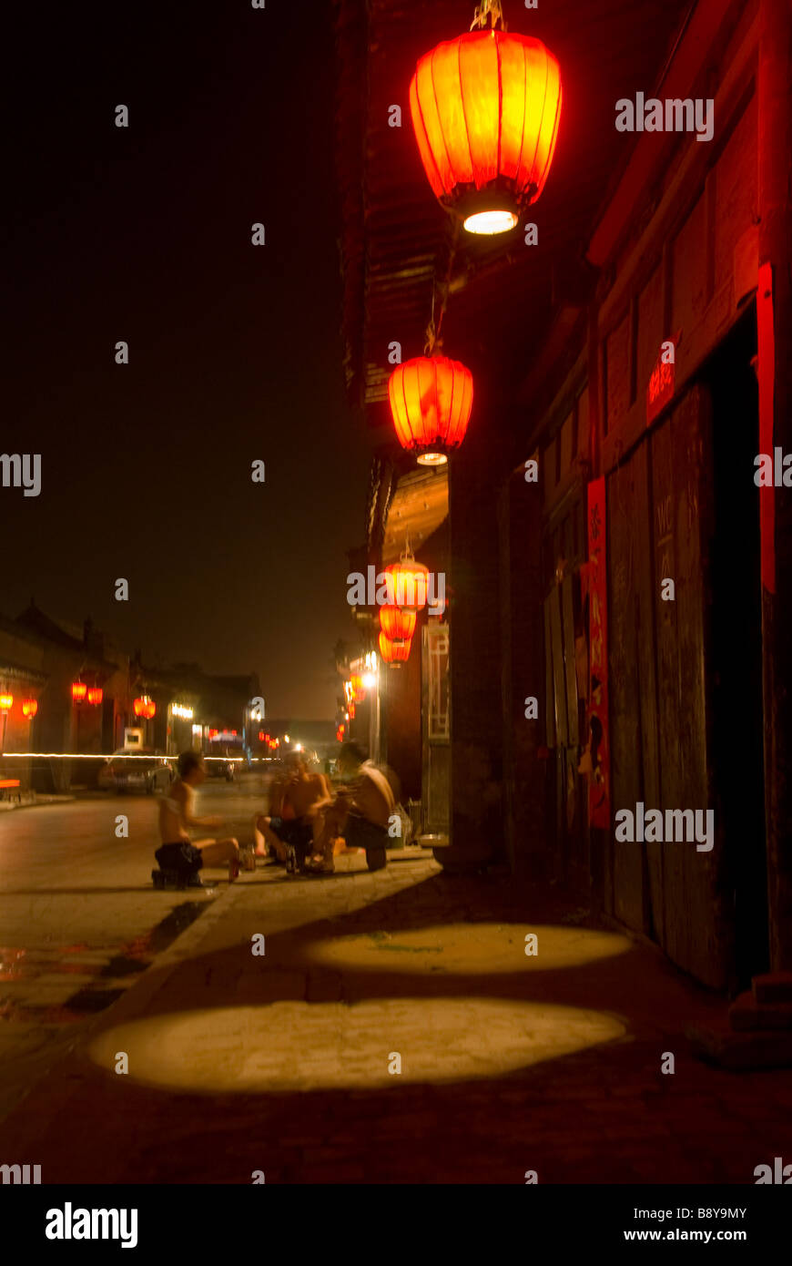 Night scene with people sitting outside in one of the streets of ...