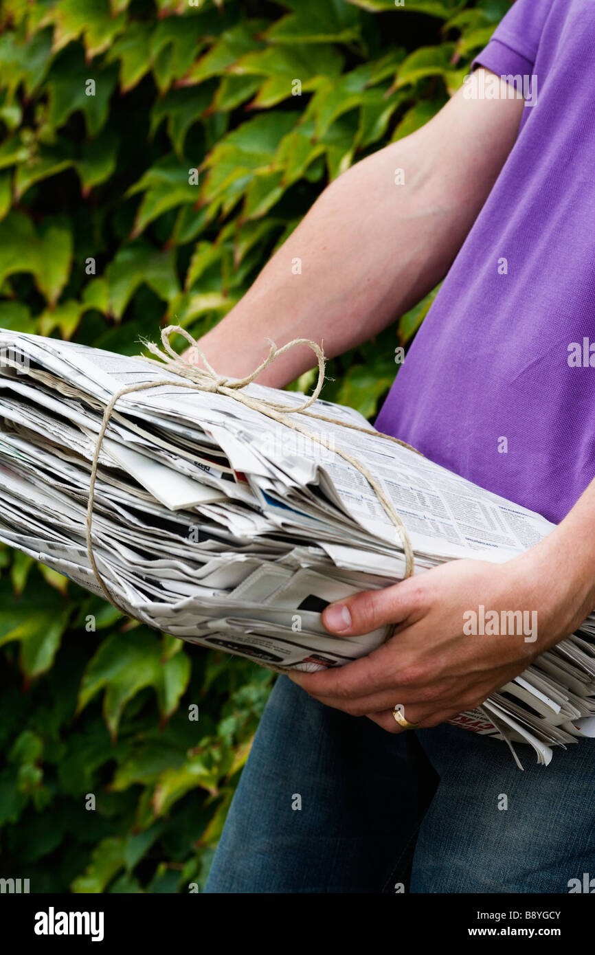 A man holding newspapers for recycling Stock Photo - Alamy