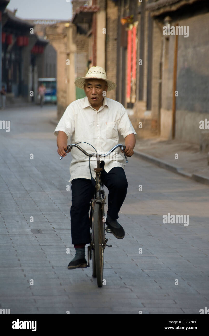Senior Chinese man riding a bike in the streets of Pingyao, Shaanxi ...