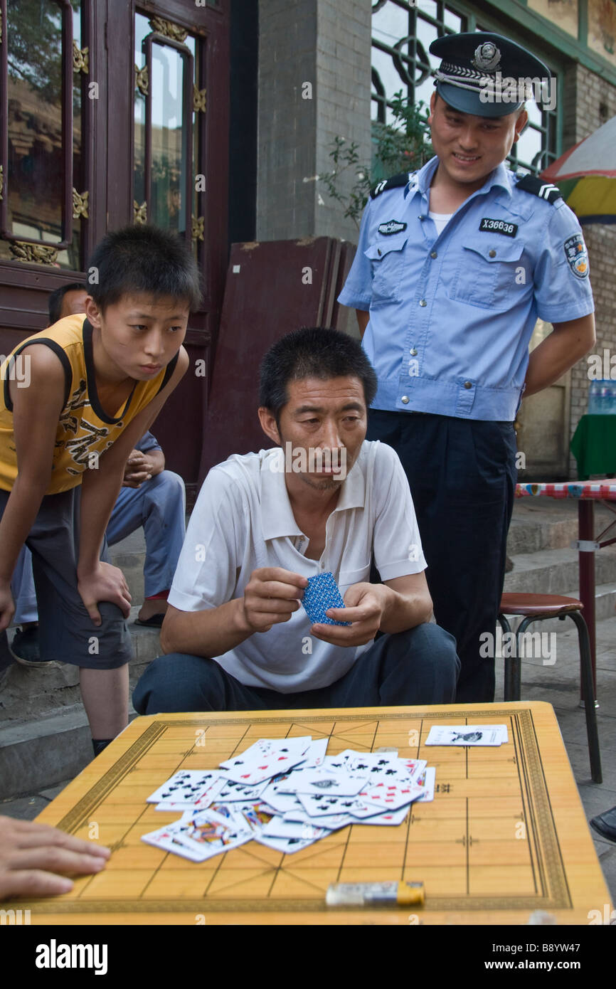 Chinese man playing a cards game under the look of a police man ...