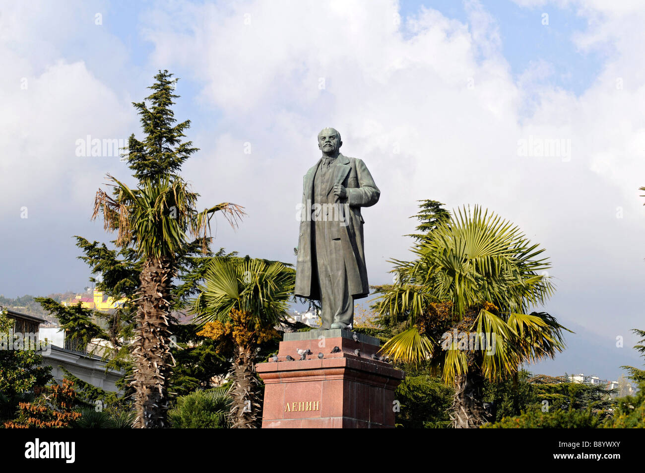 A bronze statue of Russian revolutionary Lenin stands among palm trees ...
