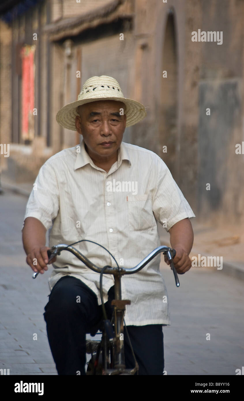 Senior Chinese man riding a bike in the streets of Pingyao, Shaanxi ...