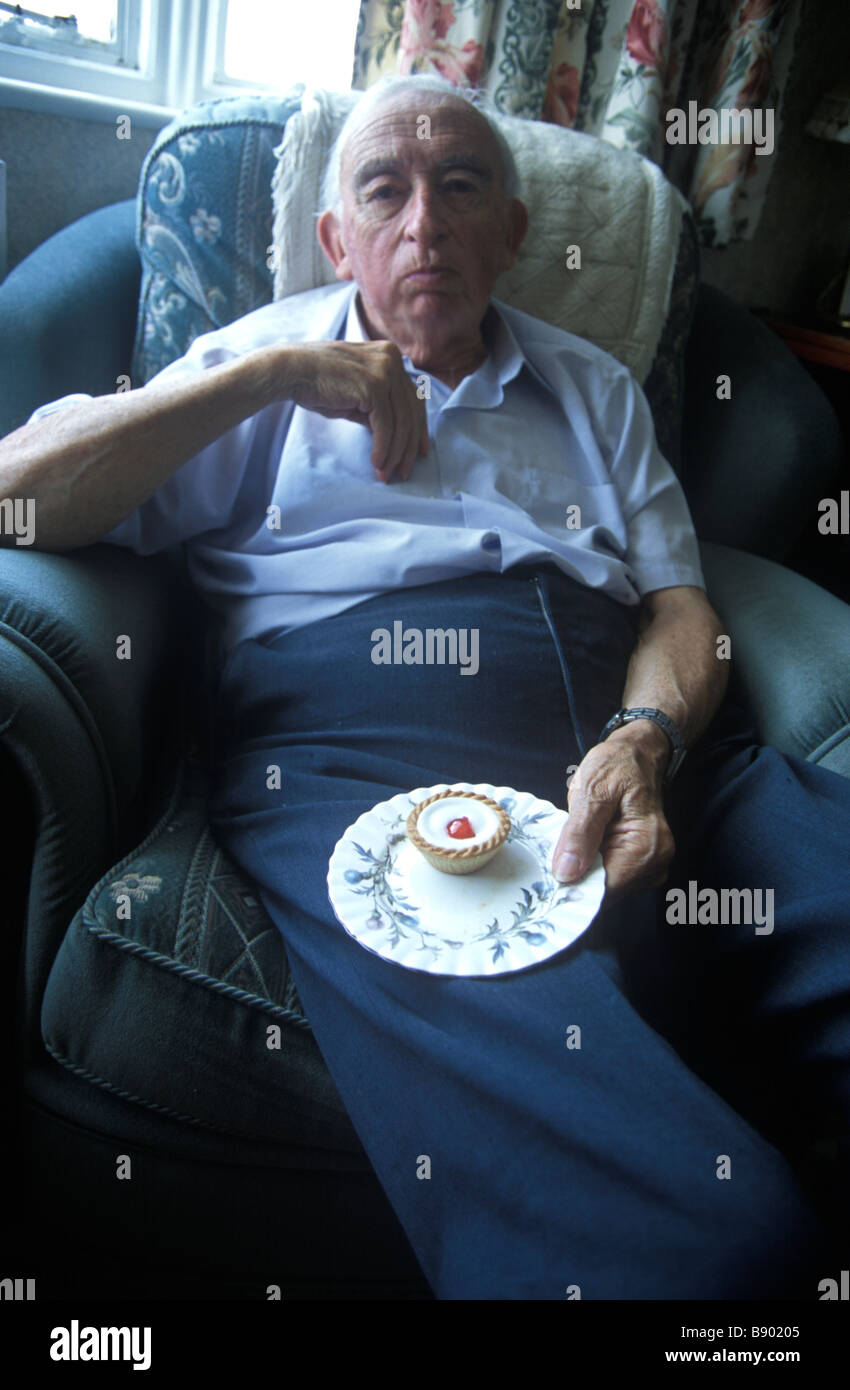 elderly man sitting in a chair eating a cake Stock Photo - Alamy