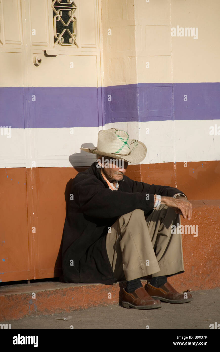 Old man with cowboy hat sitting on the doorstep of a multi coloured ...