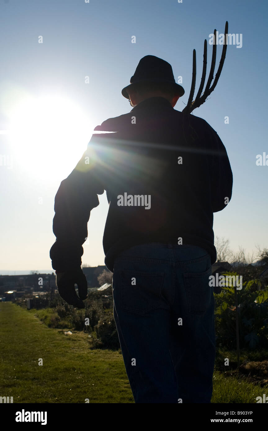 man walking with fork on allotment Stock Photo - Alamy