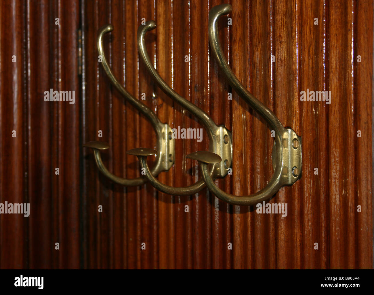 A Row of Brass Coat-hooks on a mahogany wall Stock Photo - Alamy