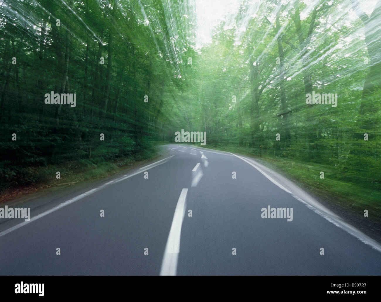 Blurred road through forest Stock Photo - Alamy