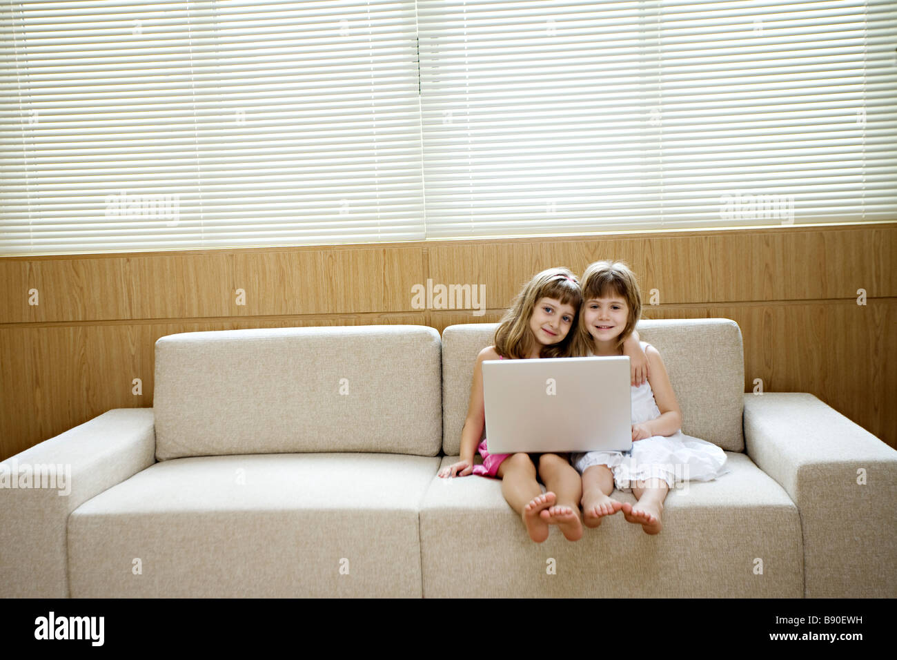 Two girls sitting in a sofa with a computer Stock Photo - Alamy