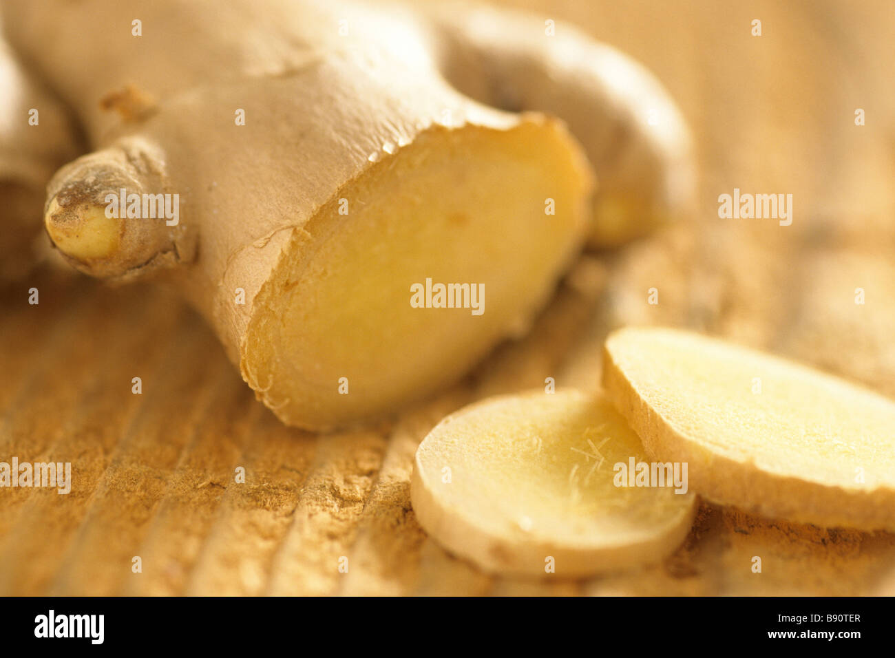 Ginger (Zingiber officinalis), root and slices on wood Stock Photo - Alamy