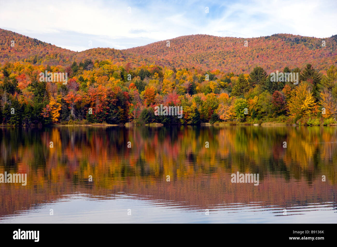 A calm lake with reflections and fall foliage color in rural Vermont ...