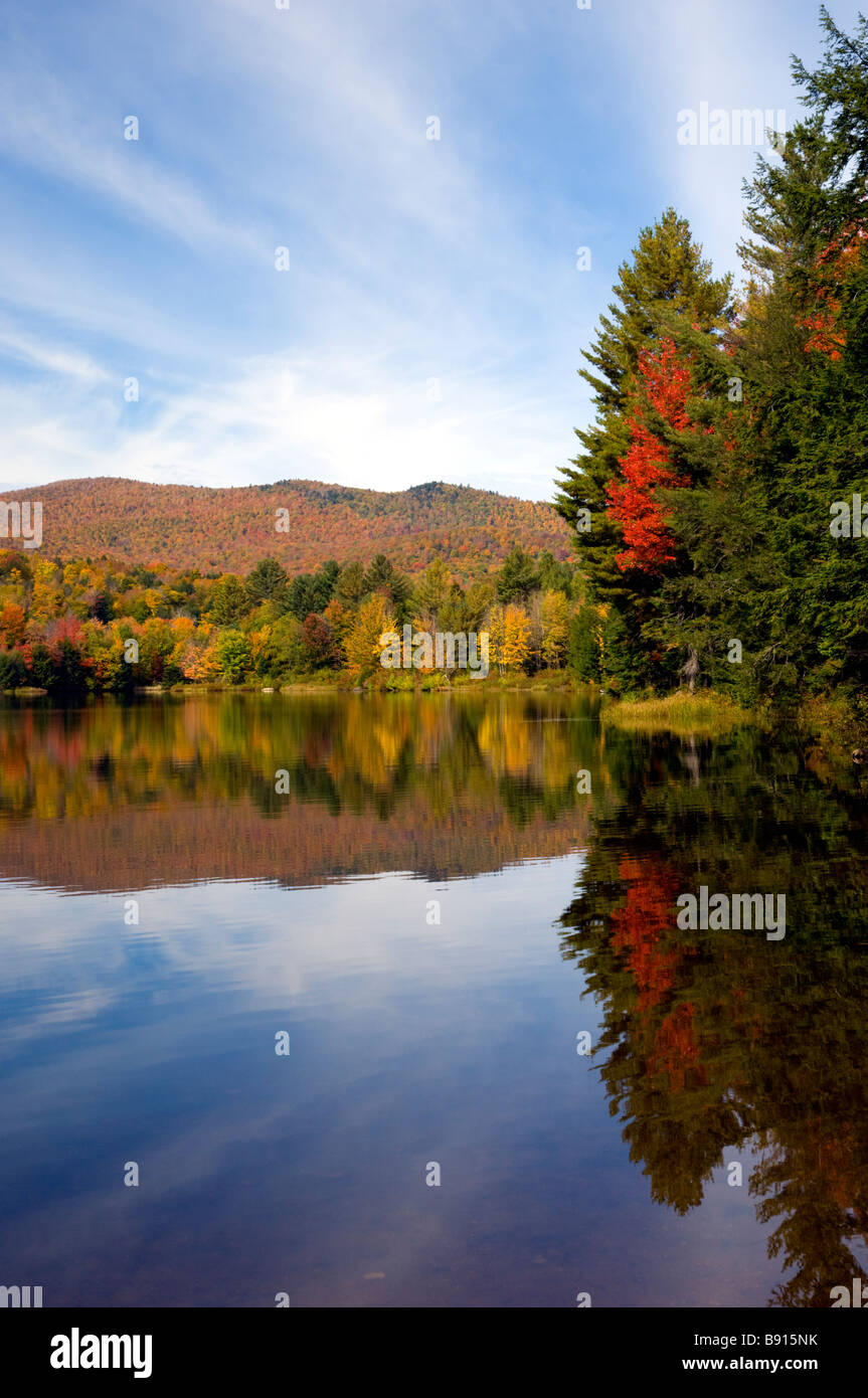 A calm lake with reflections and fall foliage color in rural Vermont ...