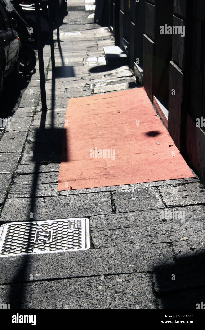 one old dirty red carpet outside shop on empty vacant sidewalk in city ...