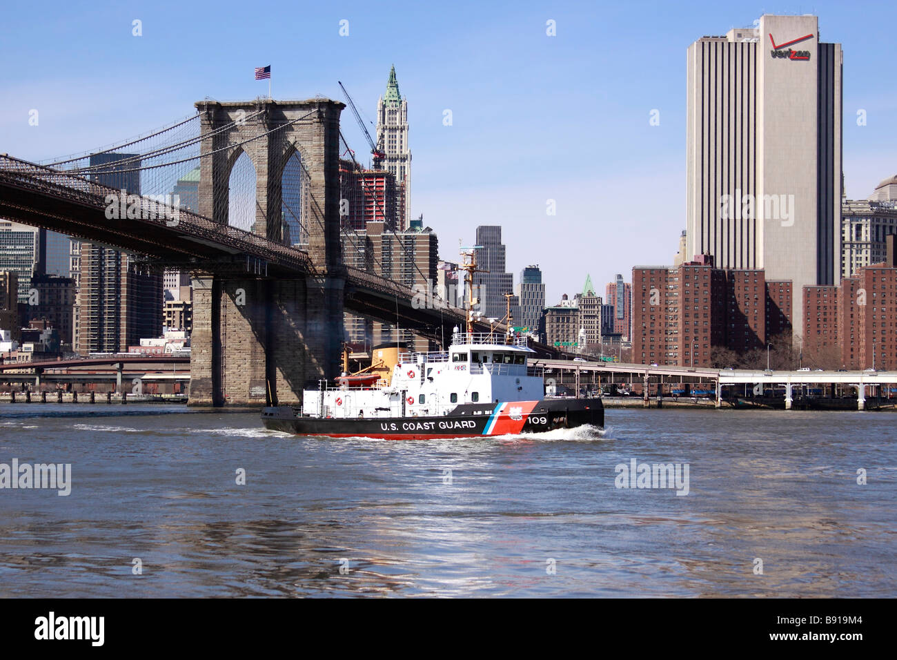Coast Guard patrol boat on East River passing under the Brooklyn Bridge ...