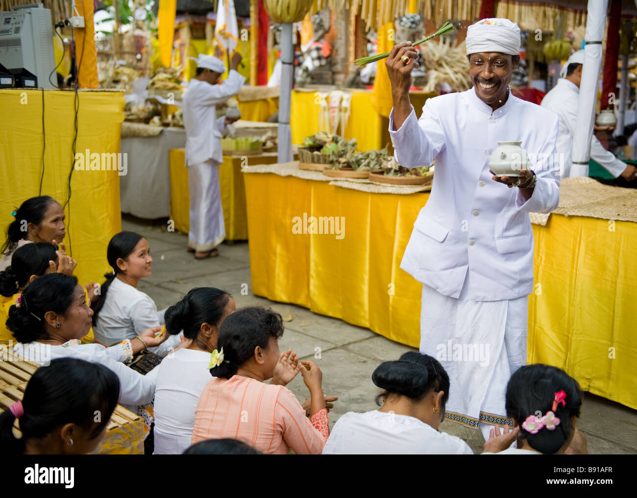 Priest sprinkling holy water on attendees in a Hindu ceremony - Bali ...