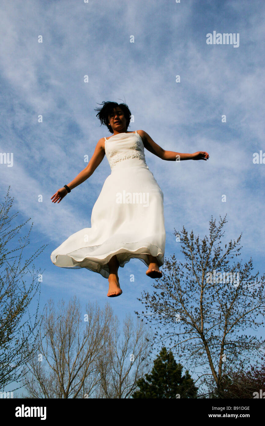 A bride jumping in her wedding dress on a trampoline Stock Photo - Alamy