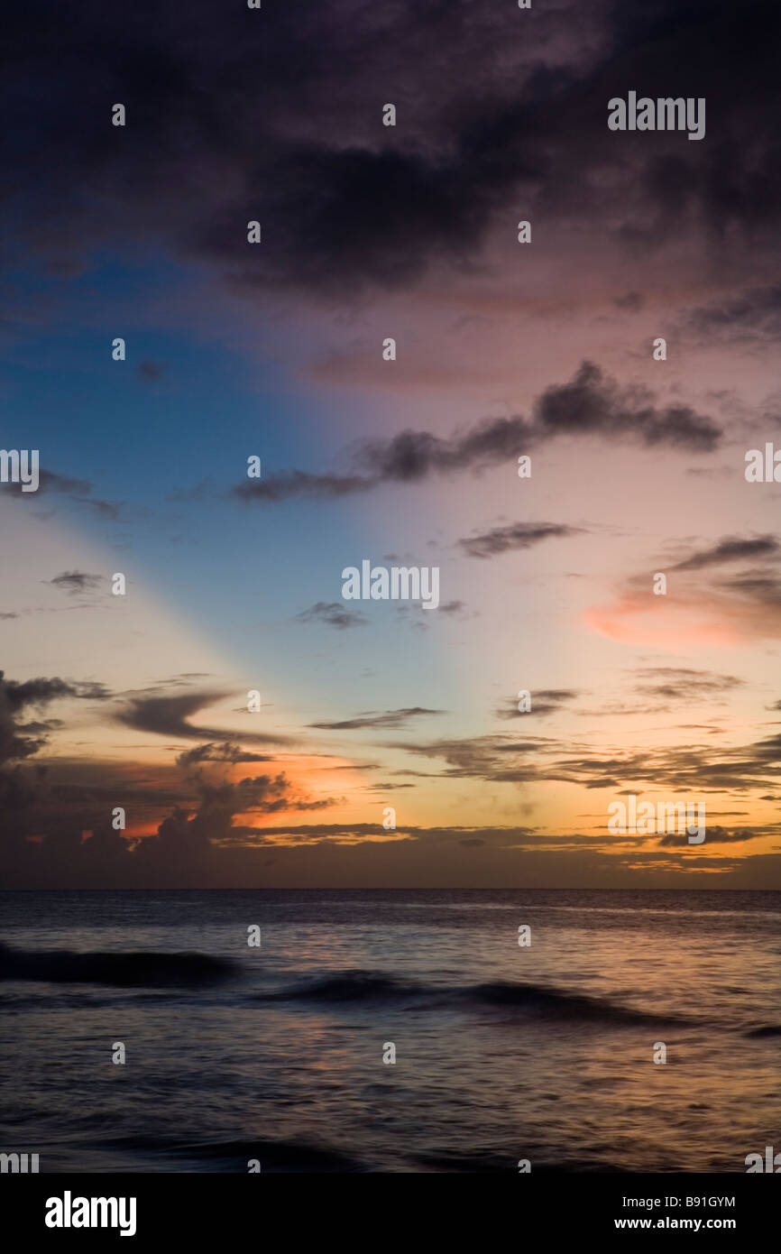 Sun setting low over ocean with rain clouds, Island of Tobago ...