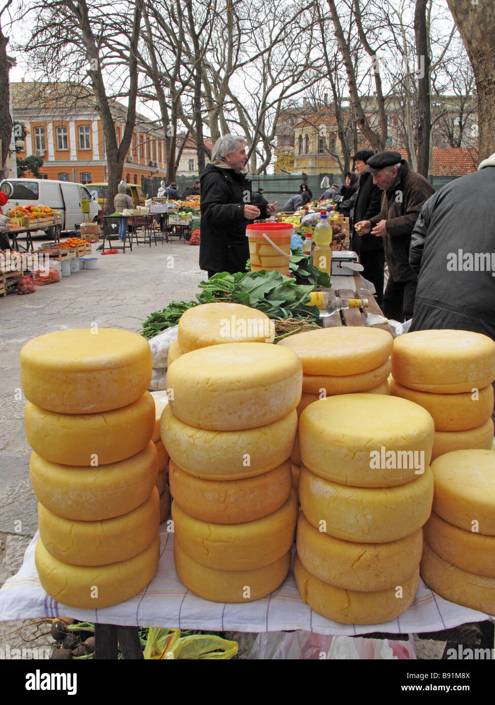 Wheels of cottage made cheese and vegetables displayed on market in ...