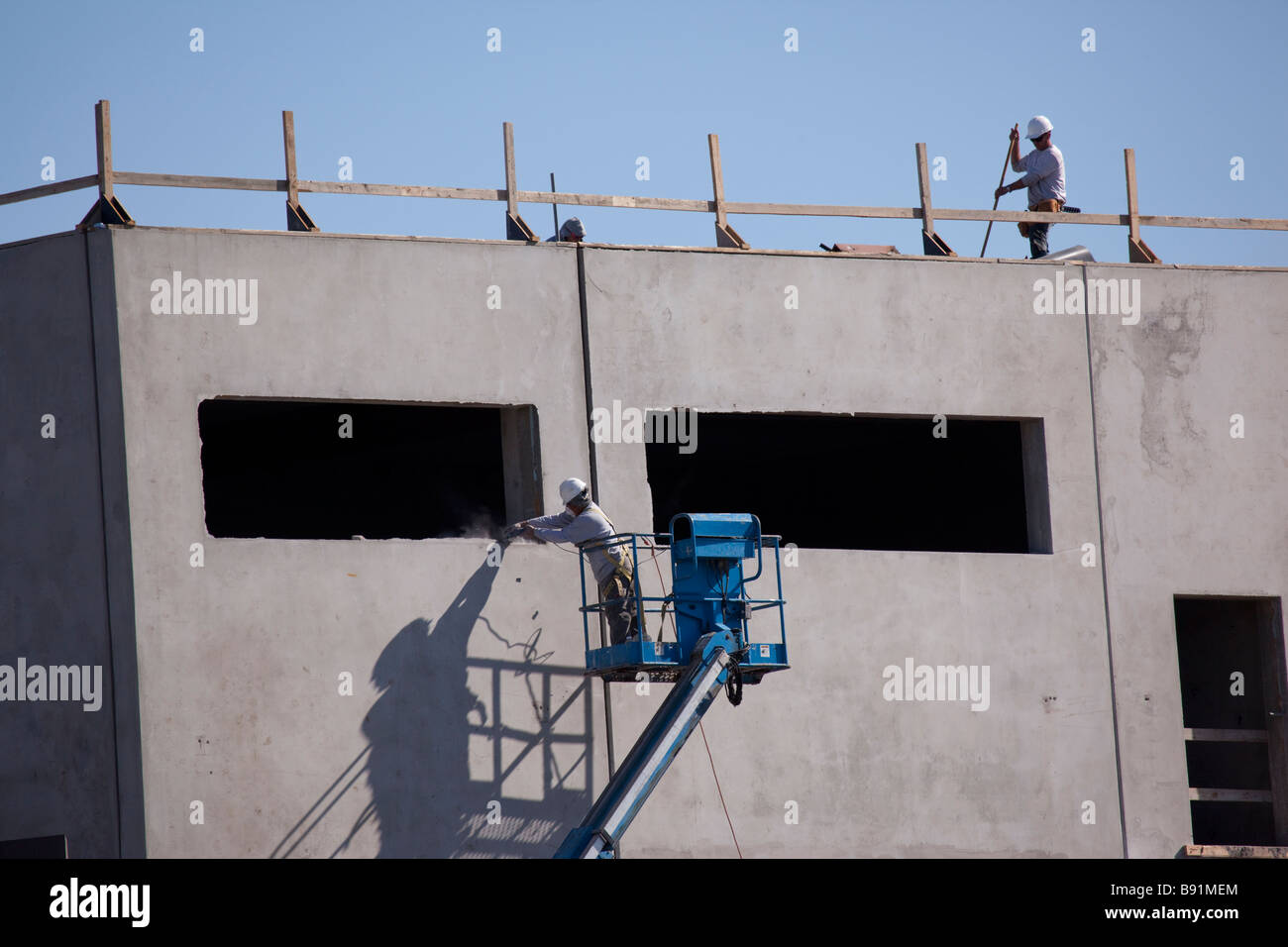 Large building construction site grinding excess concrete around window ...