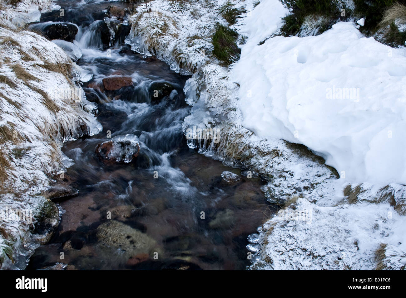 Flowing stream surrounded by ice and snow Stock Photo - Alamy