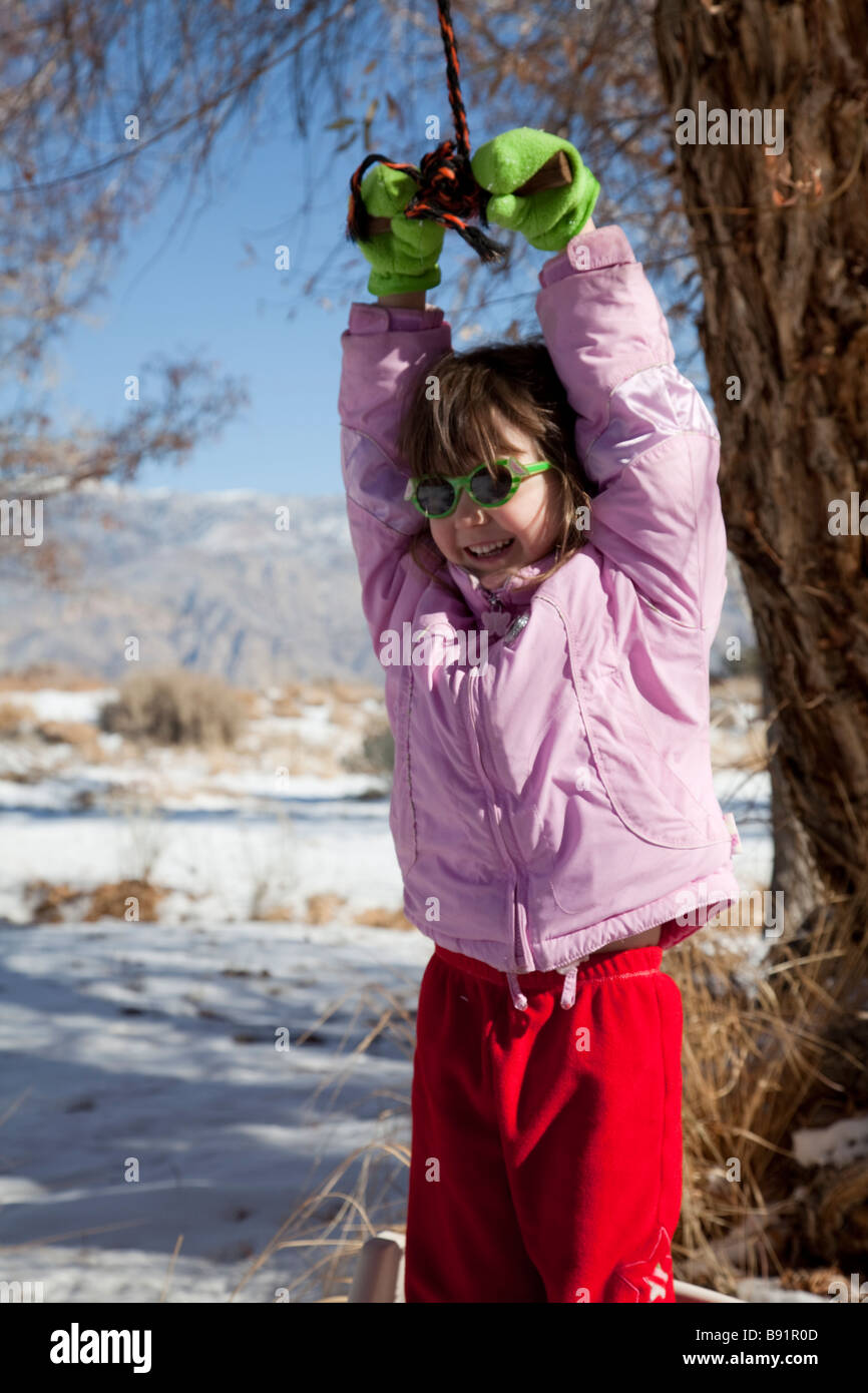 A girl hanging by a rope to swing Stock Photo - Alamy