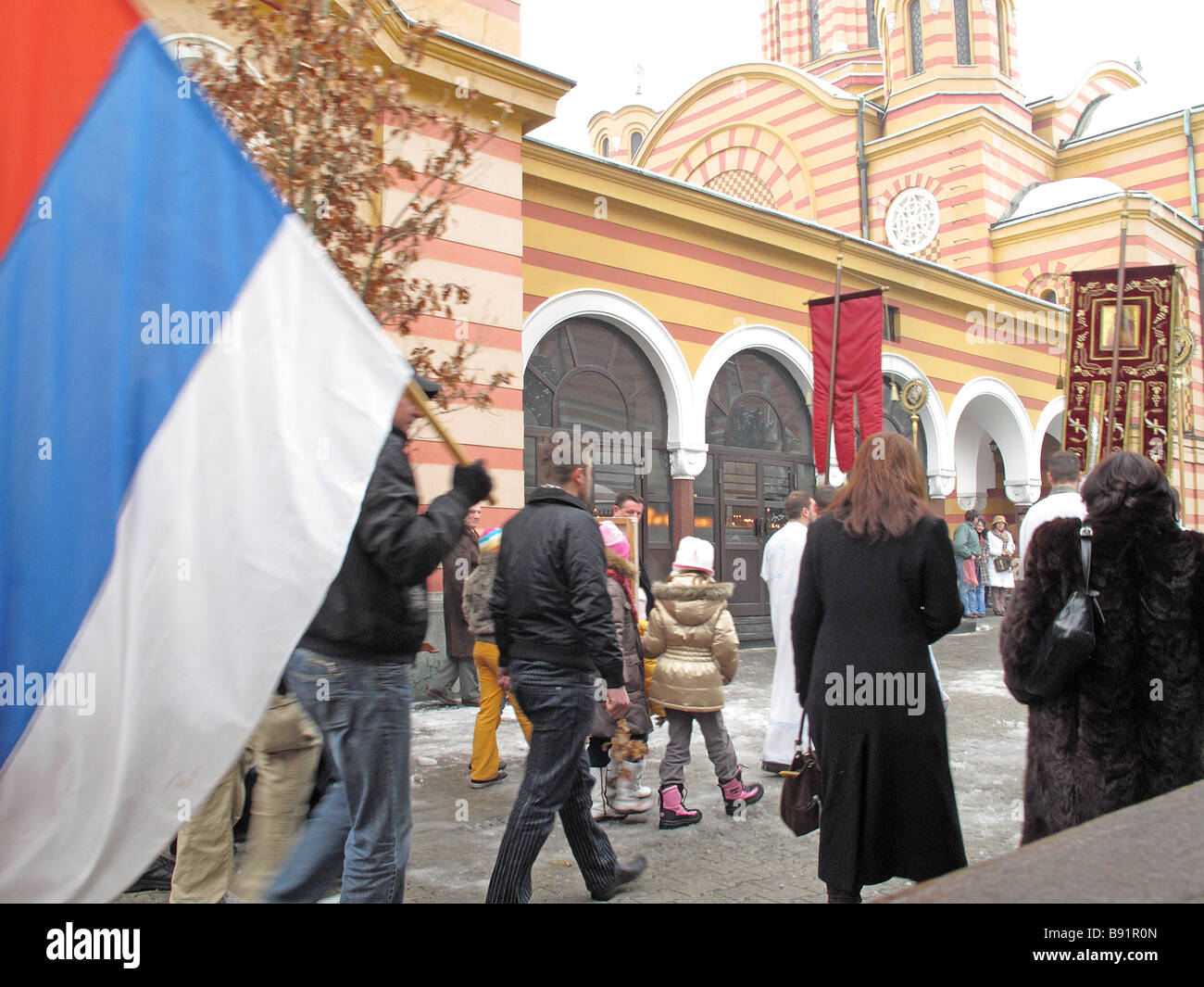 People in procession with a red blue and white Serbian flag passing by ...