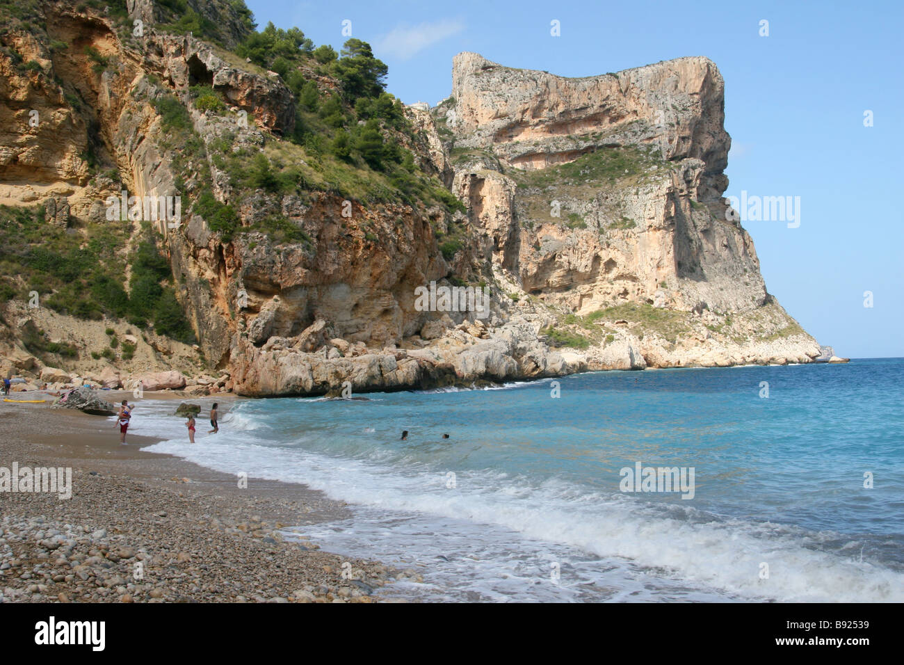 Swimmers at Playa del Moraig, Benitachell, Spain, rocky beach and large ...
